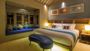 Um quarto com uma cama grande, um assento junto à janela e obras de arte na parede.