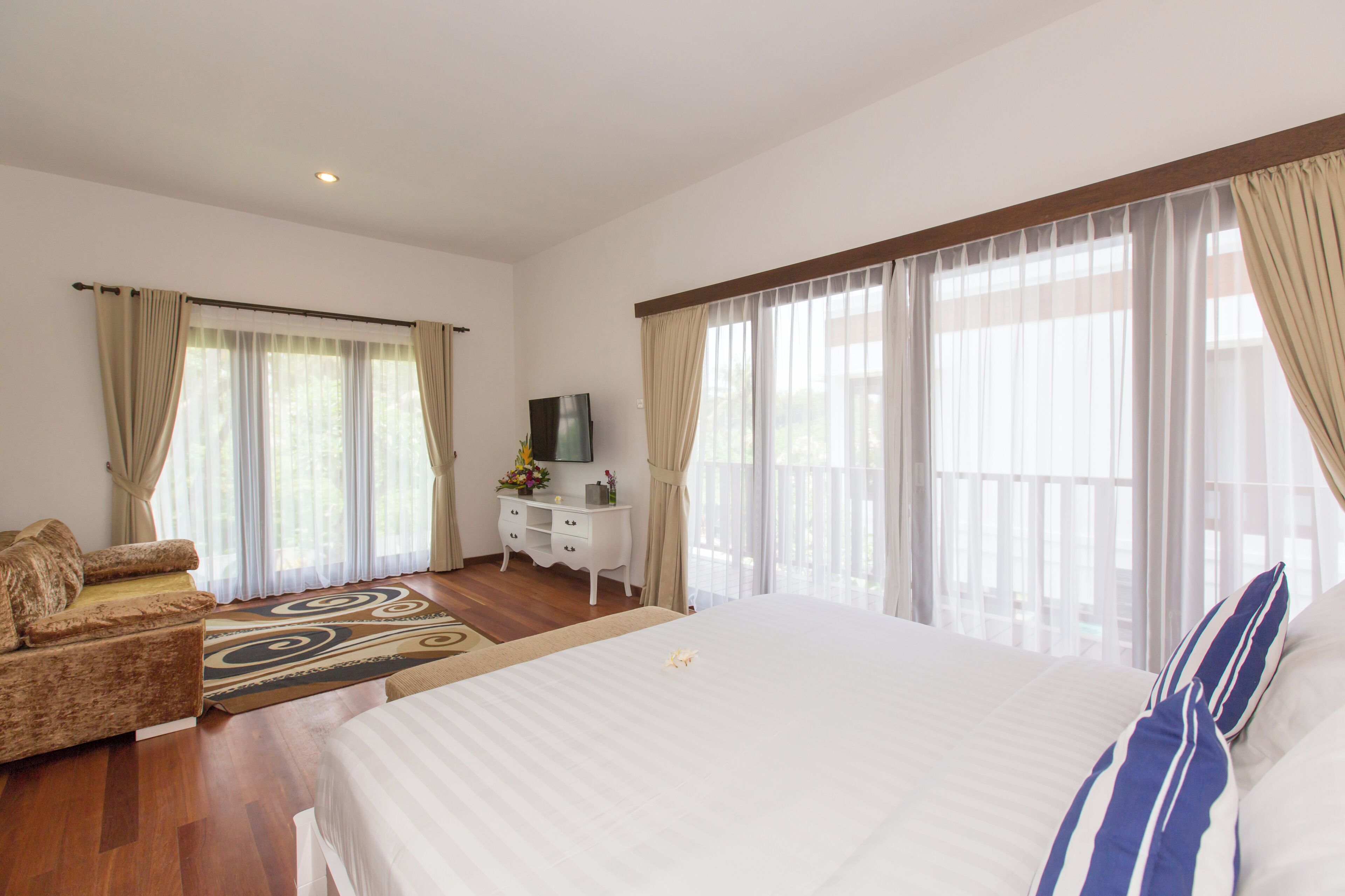 Quarto de hotel espaçoso, com uma cama grande, um sofá, uma mesa de trabalho e uma televisão.