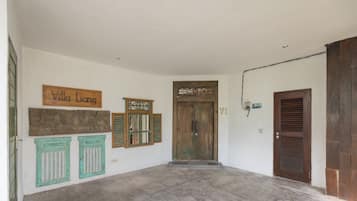 Um corredor com porta de madeira, uma placa com a inscrição 'Villa Liang' e um objeto decorativo fixado na parede.