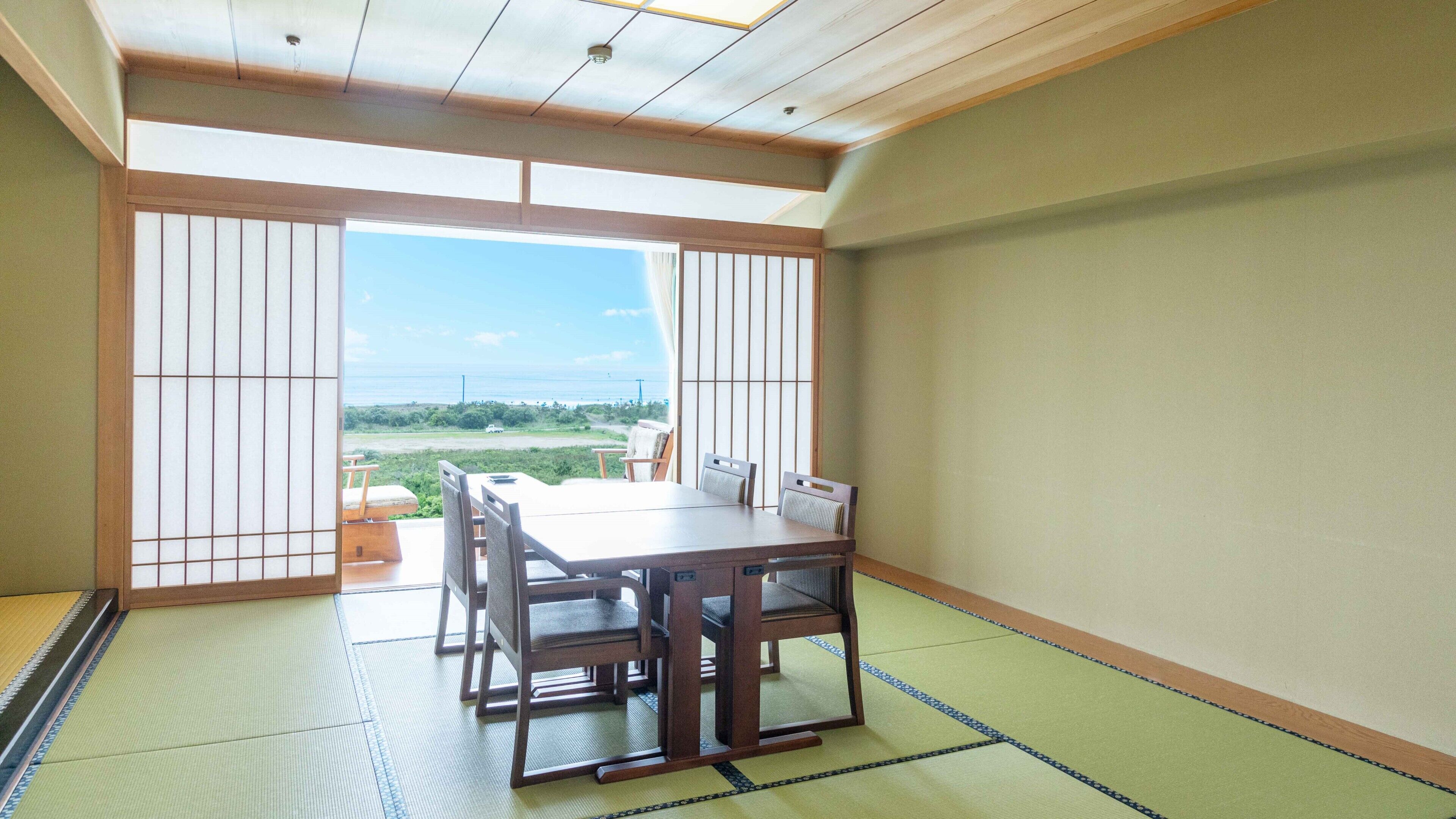 Um quarto japonês tradicional com tatames, uma mesa baixa e portas deslizantes.