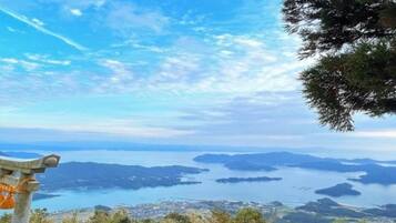 Paisagem costeira com céu claro, estrutura de pedra e vista para o mar e ilhas.