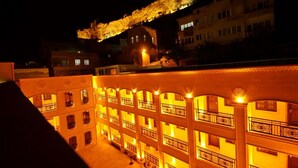 Um edifício com várias andares, varandas e fachada iluminada e acolhedora à noite.