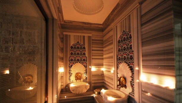 Um banheiro luxuoso, com um espelho grande, decorações elaboradas nas paredes e design moderno.
