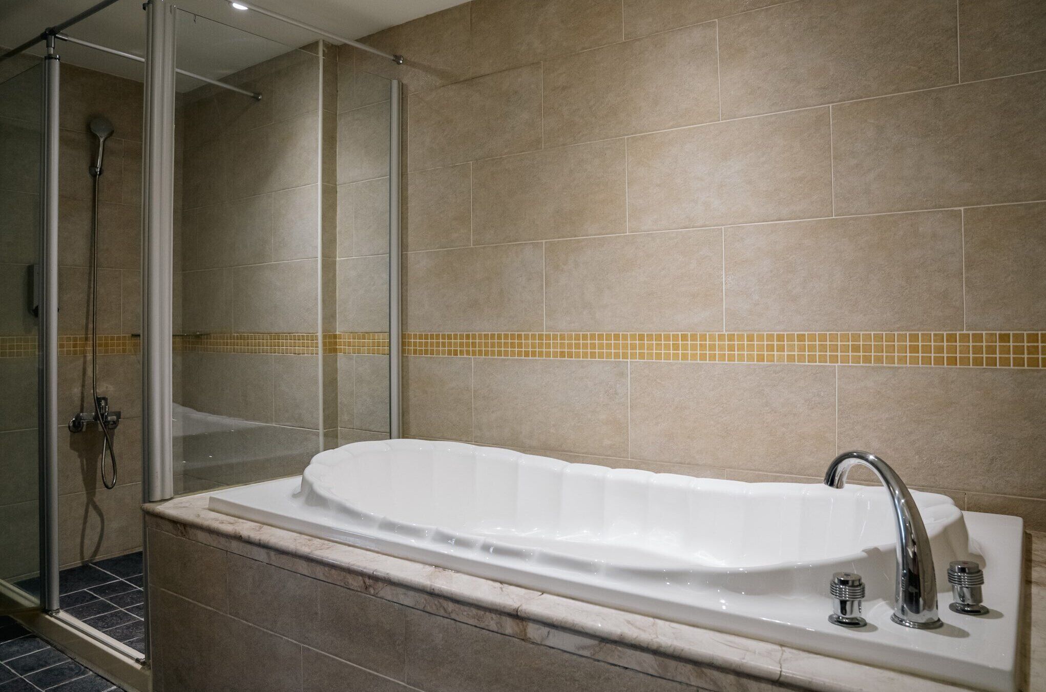 Um banheiro moderno com uma banheira livre, um box de vidro e piso revestido de azulejos.