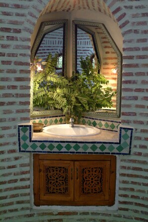 Casa de banho com janela, lavatório e azulejos decorativos.