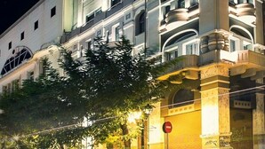 Um edifício de vários andares com design arquitetônico moderno, apresentando varandas e grandes janelas.