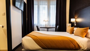 Quarto de hotel com uma cama, uma mesa e uma cadeira.