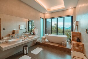 Casa de banho moderna com uma banheira grande, duas pias e um espelho amplo.