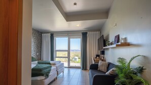Uma sala de estar moderna com um sofá, uma cama e uma janela grande com cortinas.