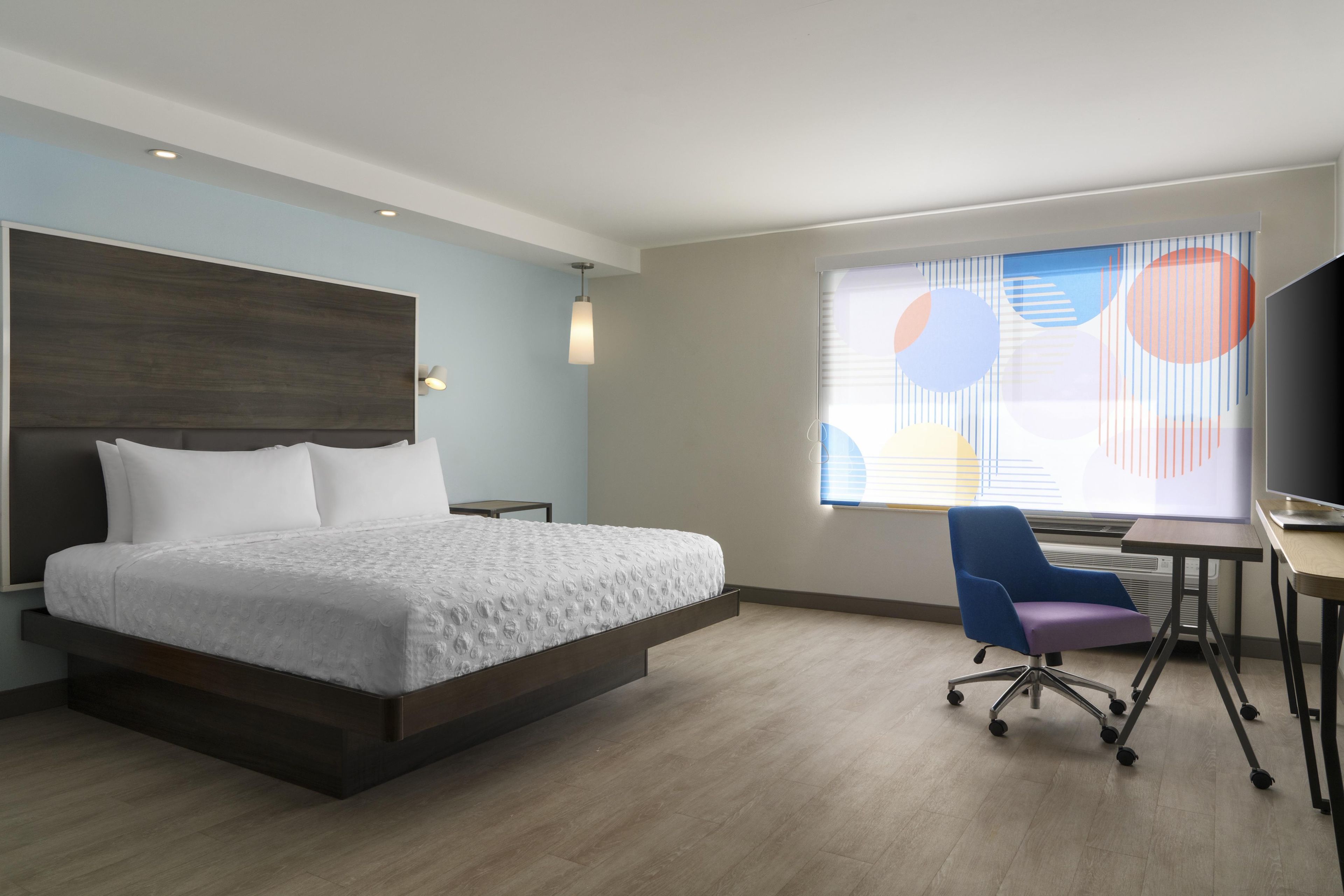 Quarto de hotel moderno com uma cama grande, uma escrivaninha e uma cadeira.