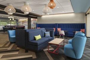 Espaço lounge moderno com assentos azuis, mesa de centro e iluminação decorativa.