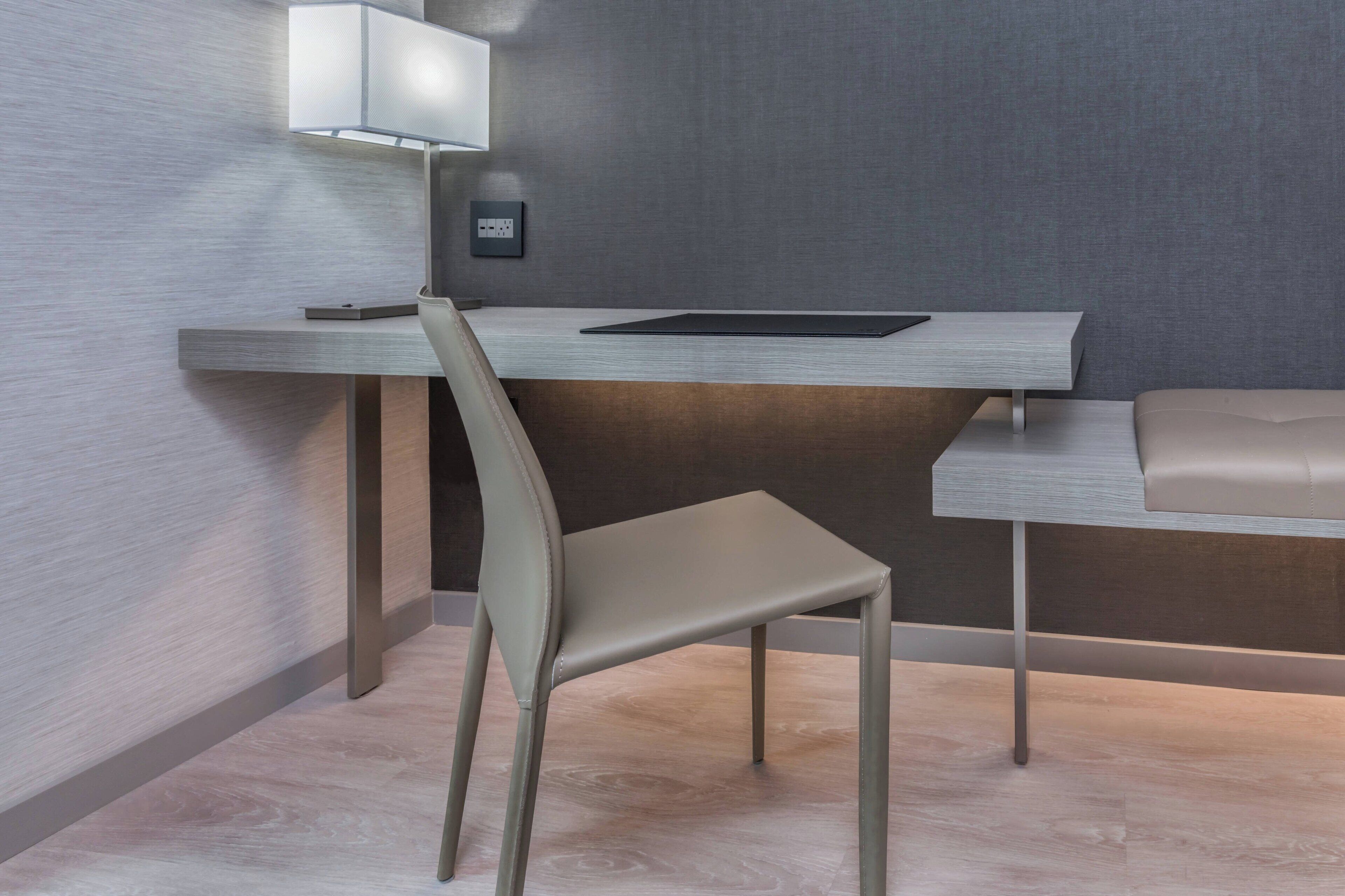 Um espaço de trabalho moderno com uma mesa, cadeira e luminária.