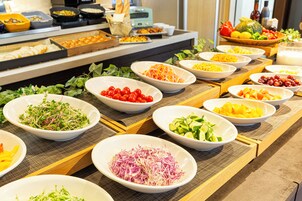 Buffet com diversos pratos, incluindo saladas, frutas e legumes.