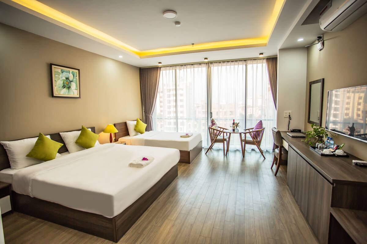 Quarto de hotel com uma cama grande, uma mesa de trabalho, uma cadeira e vista para a cidade.