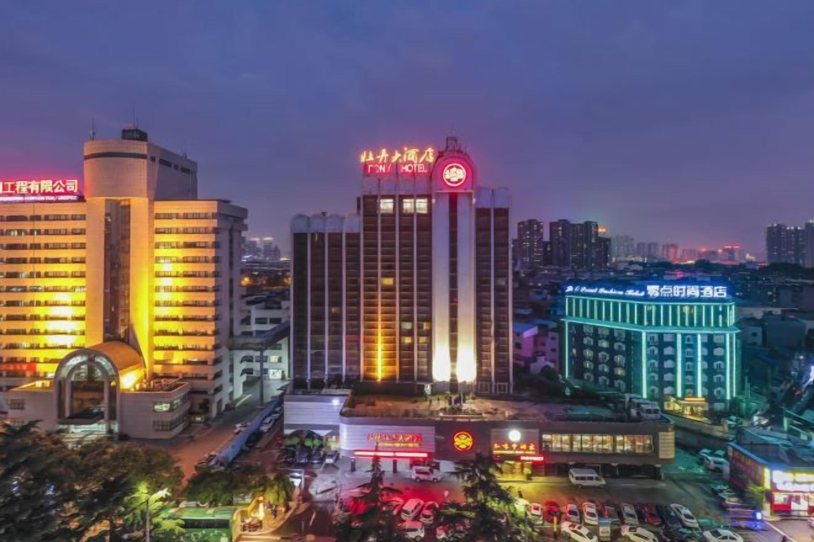 Paisagem urbana com edifícios iluminados, incluindo um hotel com uma placa visível.