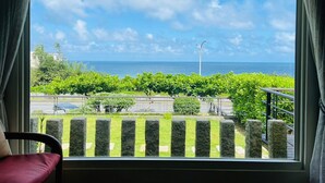 Quarto com vista para o mar, varanda com corrimão e cadeira com almofada.