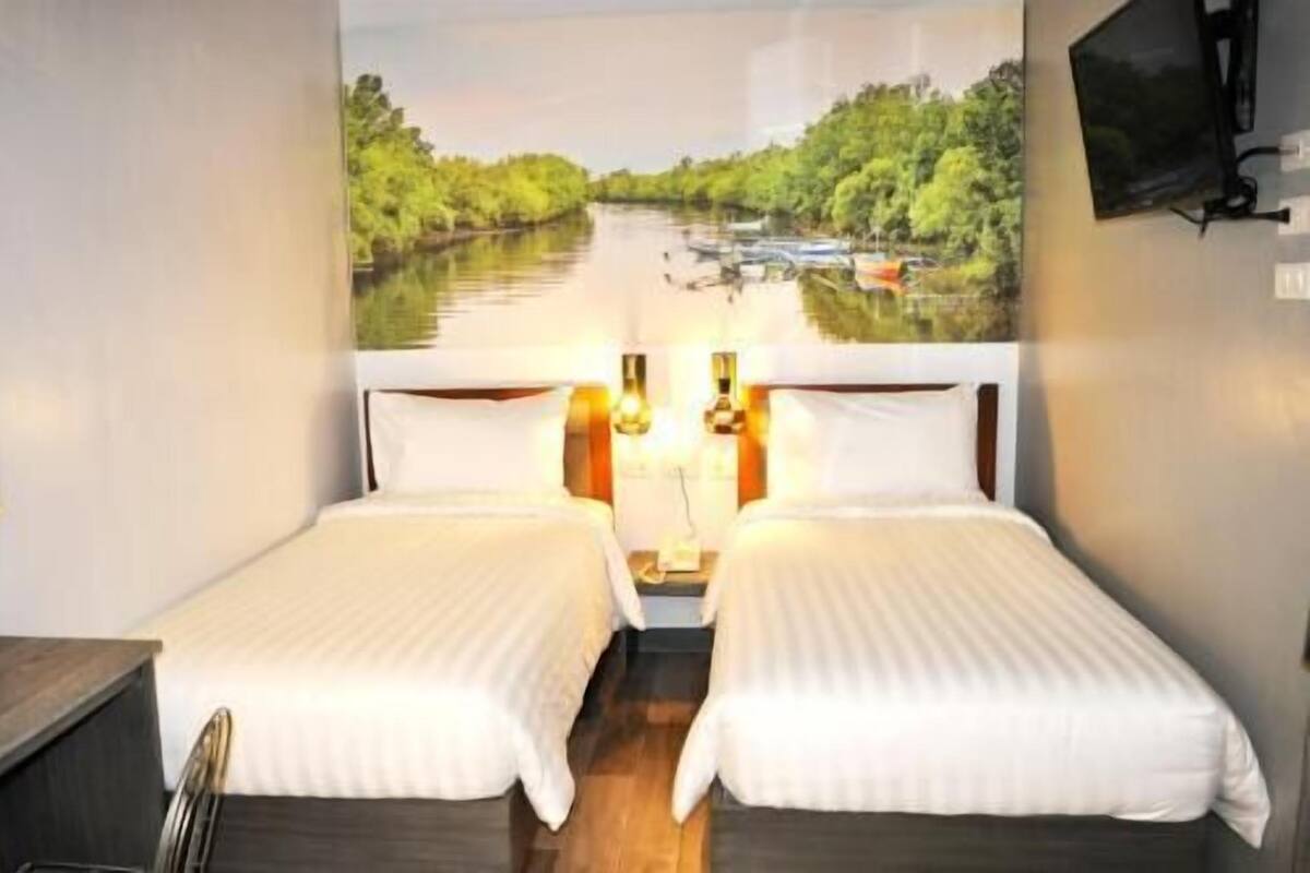 Quarto de hotel com duas camas, vista para o rio e televisão na parede.