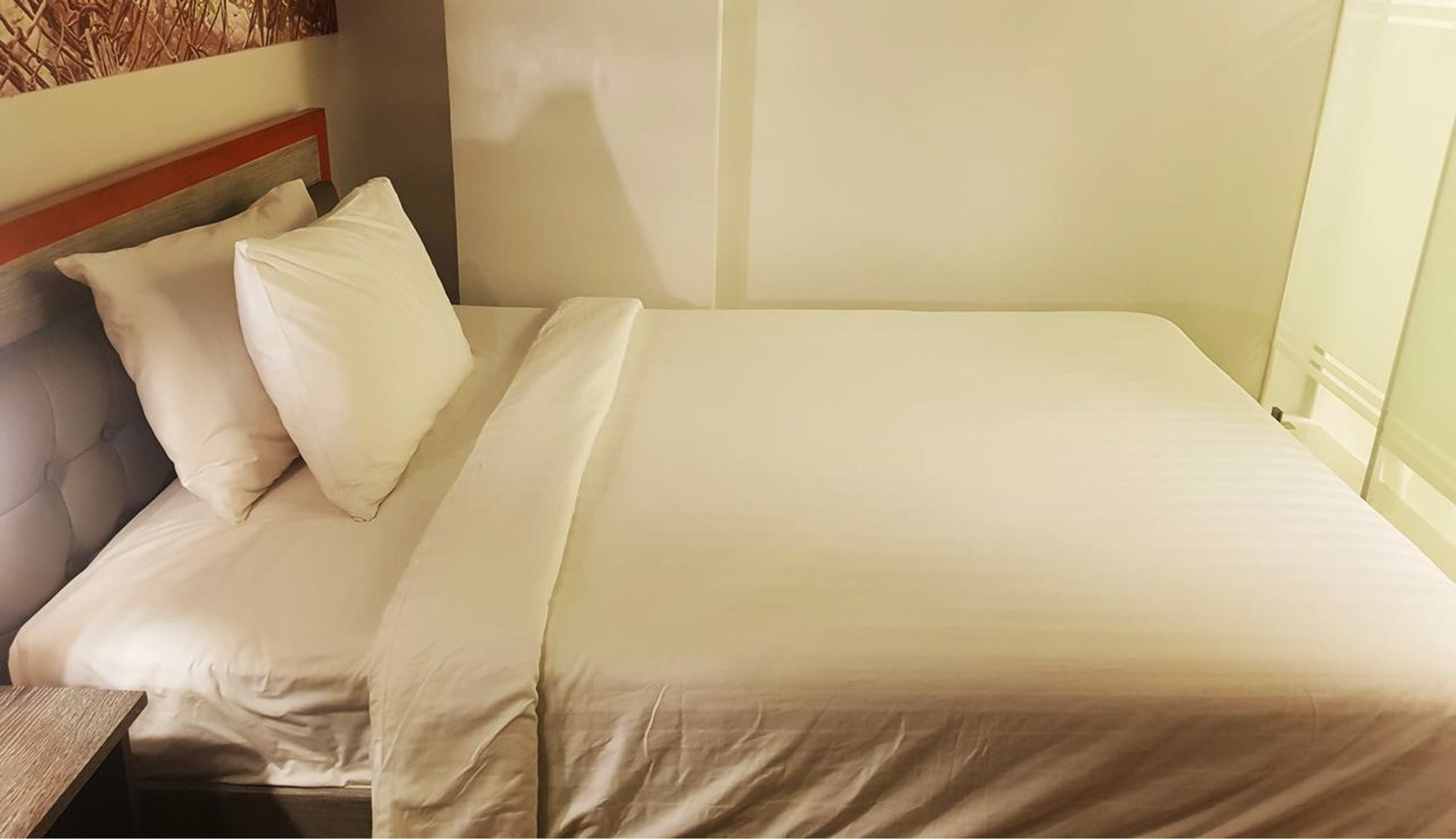 Cama bem arrumada com lençóis brancos em quarto de hotel.