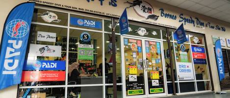 Vitrine com grandes janelas exibindo diversos artigos e uma placa indicando Borneo Speedy Dive & Tour SDN. BHD.