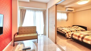 Quarto de hotel com sofá, duas camas, televisão e ar condicionado.