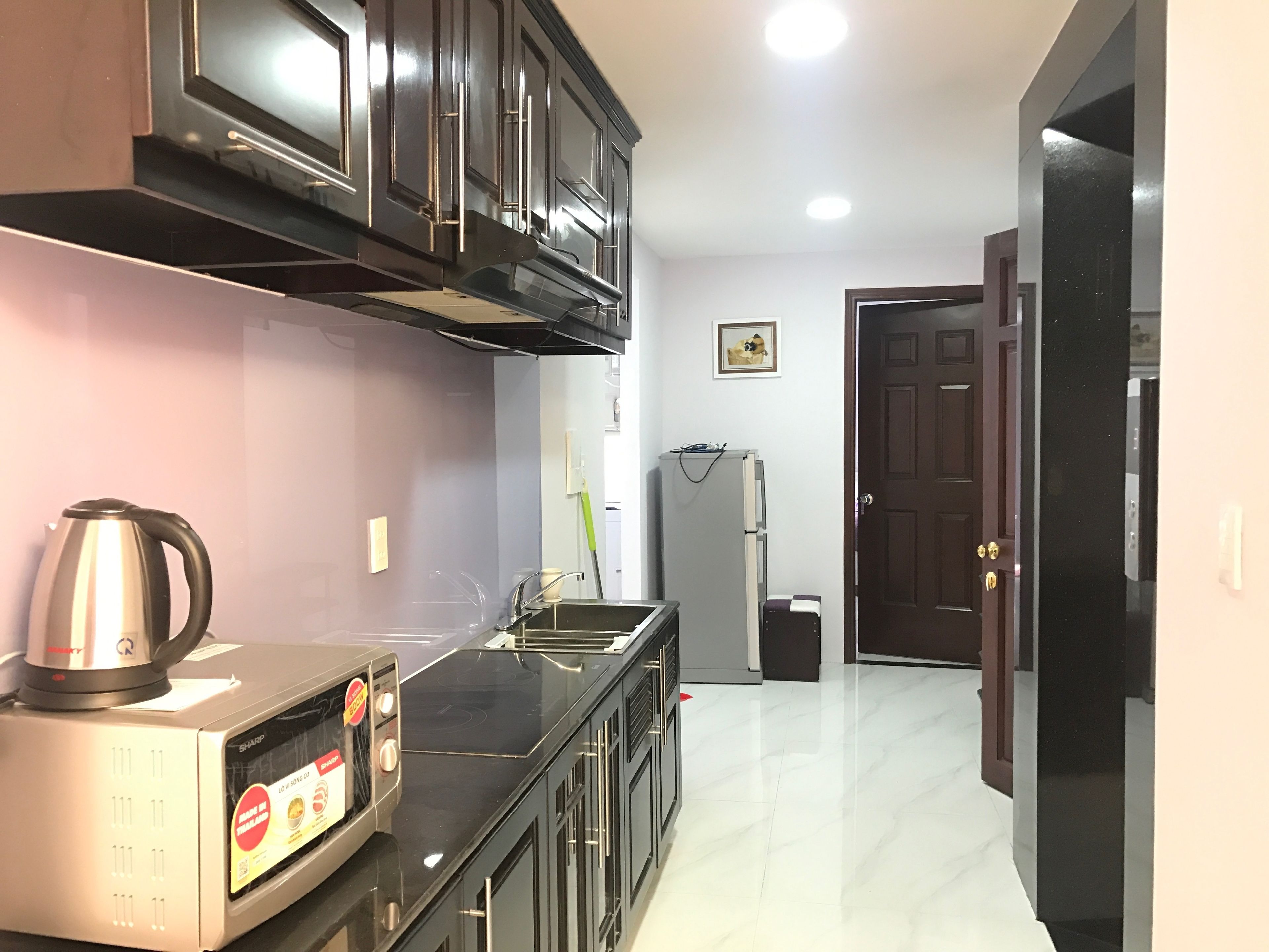 Uma cozinha moderna com micro-ondas, chaleira e frigorífico.