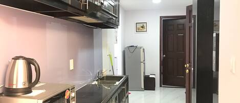 Uma cozinha moderna com micro-ondas, chaleira e frigorífico.