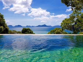 Vista clara de uma piscina com vista para o mar e ilhas ao longe.