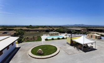 Um imóvel residencial com piscina, alpendre coberto e vista para o campo.
