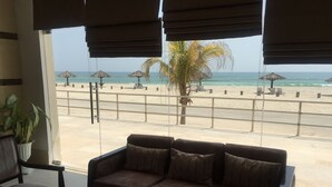 Quarto com sofá e cadeiras voltado para a vista da praia.