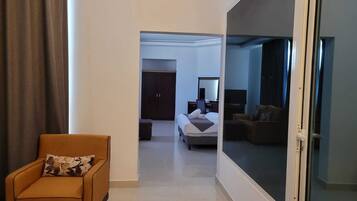 Quarto de hotel com sofá, cama, guarda-roupa e uma janela grande.