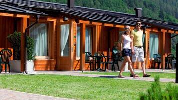 Uma cabana de madeira com varanda coberta, espaço para sentar ao ar livre e vista para as montanhas arborizadas.