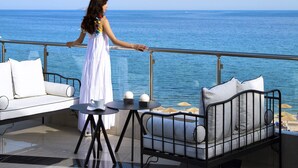 Mulher de vestido branco numa varanda com vista para o mar.