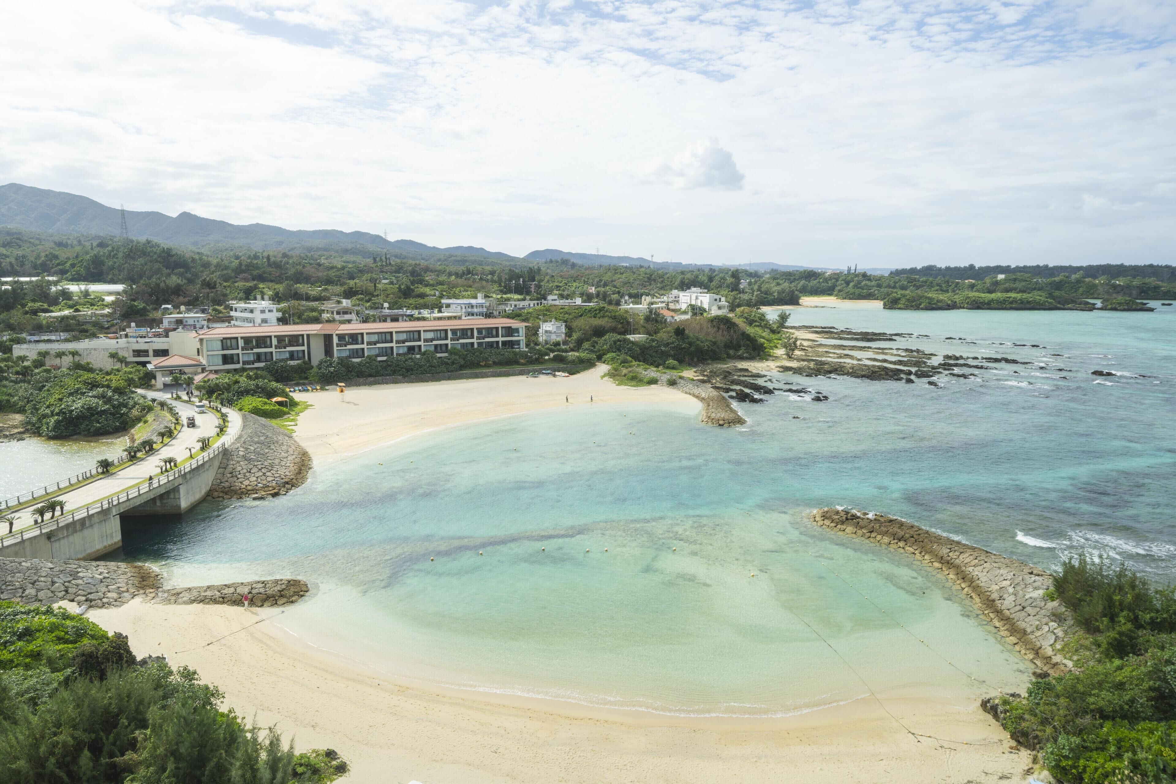 Uma área costeira com praia, uma ponte e edifícios.