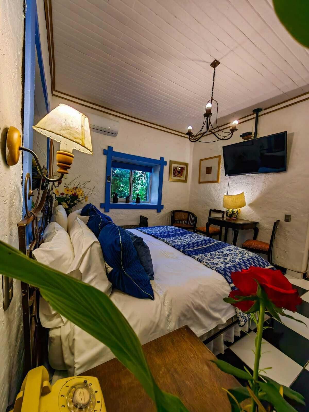Quarto com duas camas, televisão, lustre, janela e telefone.