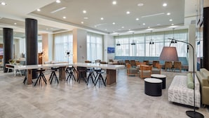 Um hall amplo com bar central, áreas de estar e grandes janelas que proporcionam luz natural.
