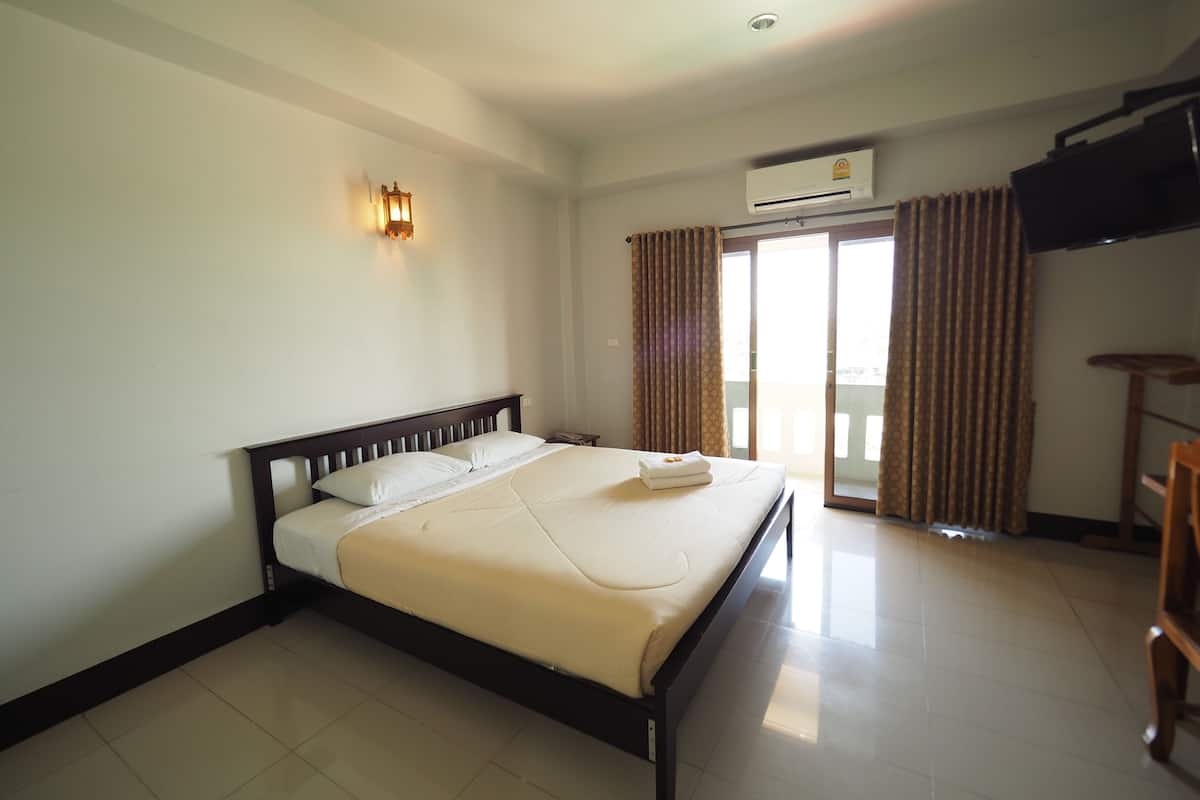 Quarto de hotel com cama, televisão de tela plana, ventilador de teto e janela com cortinas.