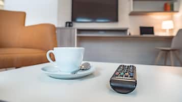 Um controle remoto e uma xícara sobre uma mesa num quarto de hotel.