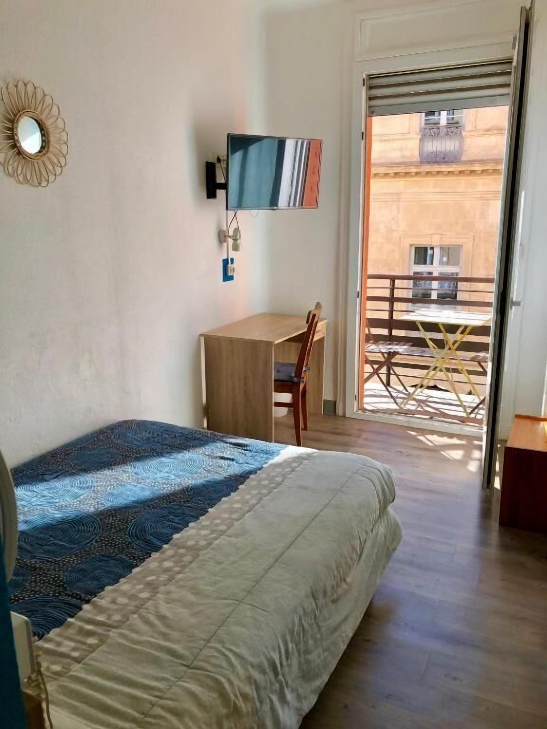 Quarto com cama, escrivaninha e cadeira. Varanda com mesa e cadeiras.