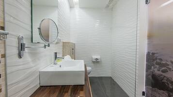 Casa de banho com lavatório branco, espelho e sanita.