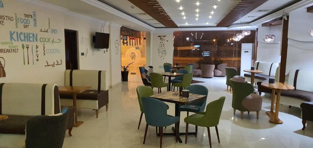 Interior moderno de restaurante com diversas opções de assento, incluindo boxes e mesas, e uma parede com palavras relacionadas a comida.