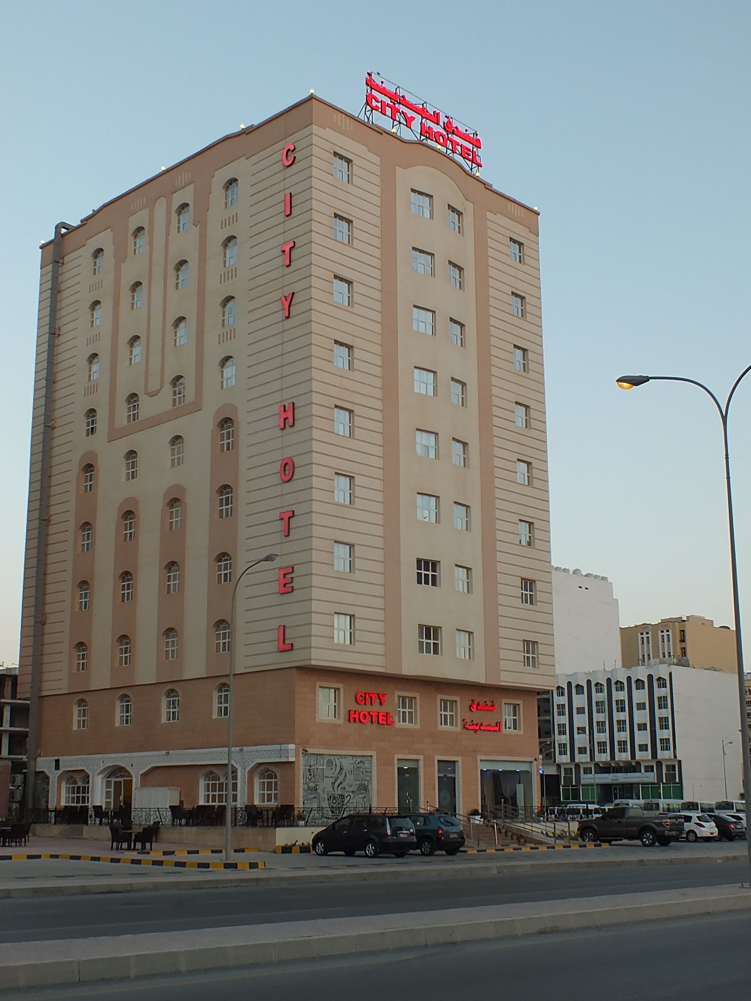 Edifício de um hotel urbano com vários andares e uma placa grande no topo.