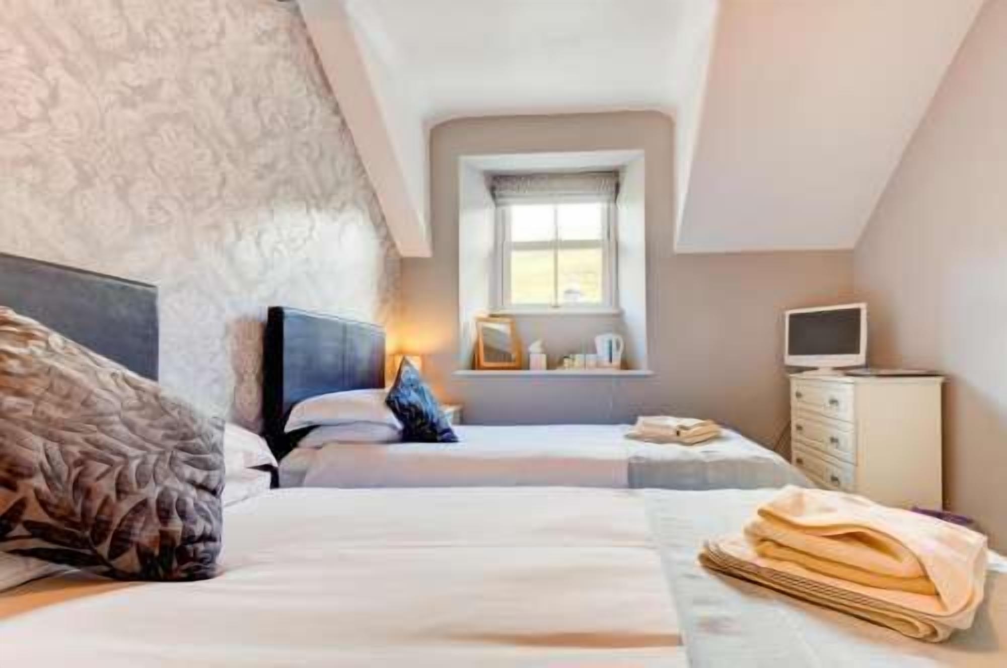 Quarto com duas camas, uma janela, uma televisão e um armário.