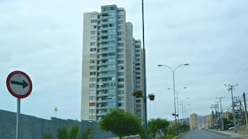 Um prédio residencial alto com uma rua ampla à frente.