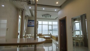 Uma sala de estar moderna com uma janela ampla, área de jantar e espaço de estar com vista para o mar.
