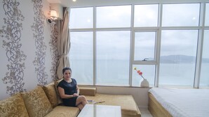 Um quarto com uma janela grande, um sofá, uma cama e uma mesa pequena.