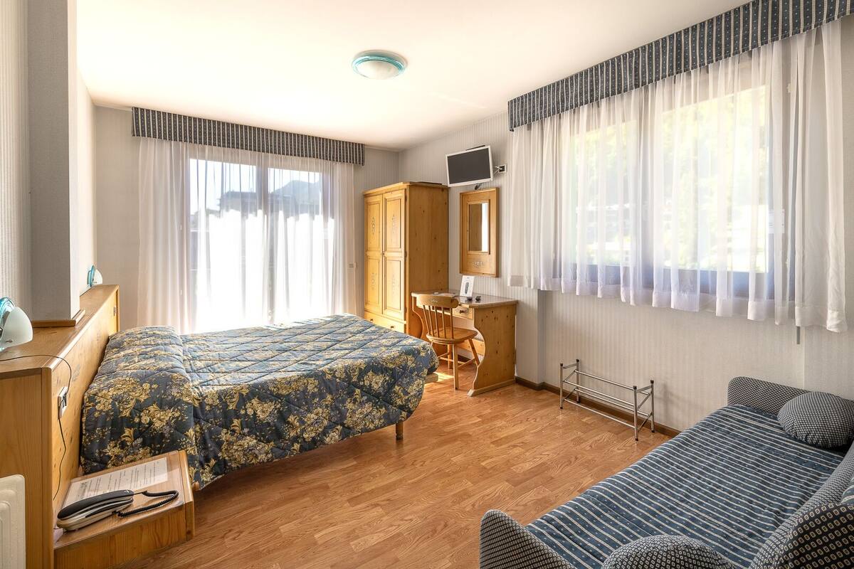 Um quarto aconchegante com uma cama, uma escrivaninha, uma cadeira e um sofá.