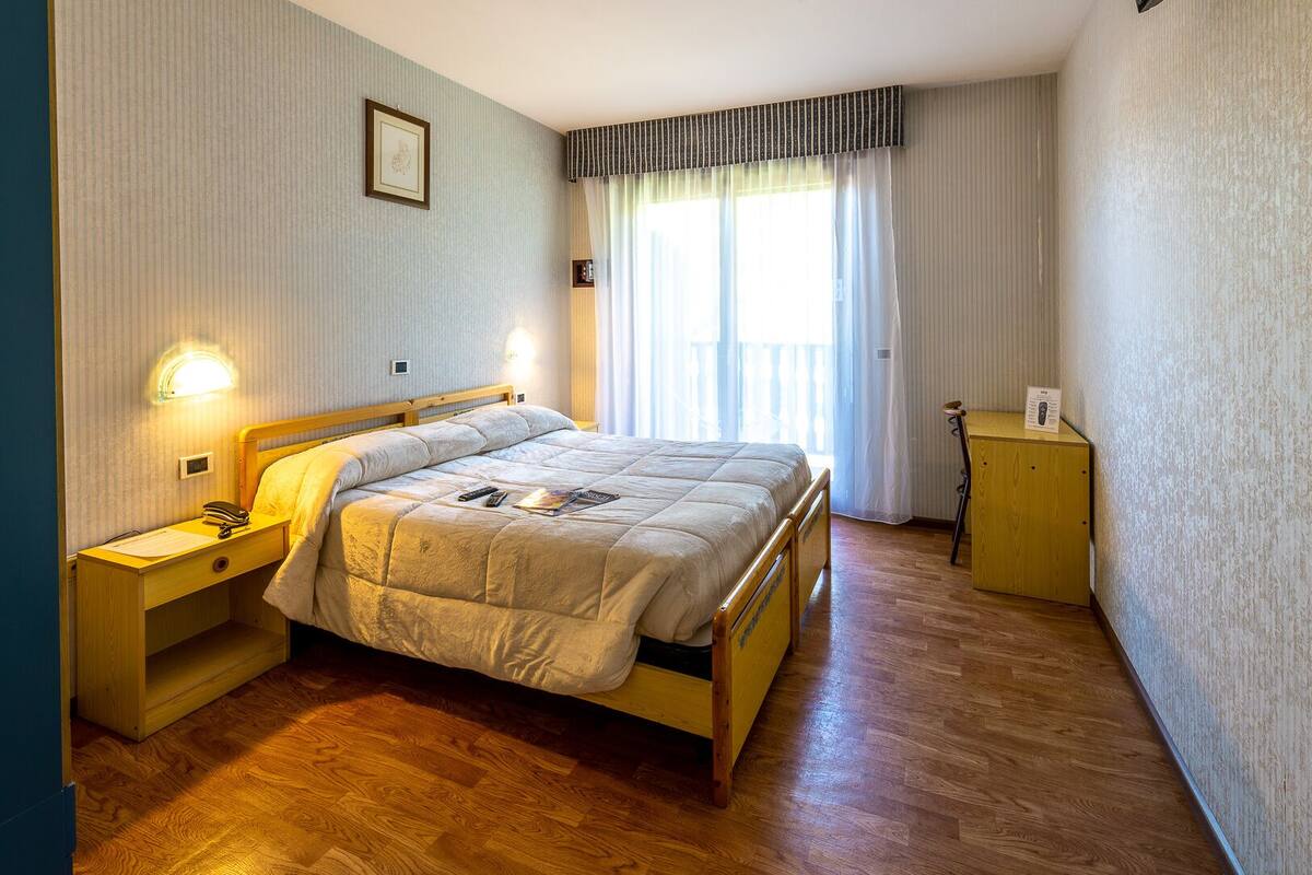 Quarto com cama de madeira, mesa de cabeceira e um pequeno armário de madeira.