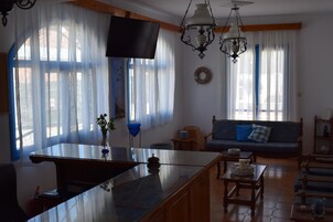 Uma sala de estar com sofá, mesa de centro, televisão e lustre.