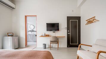 Quarto moderno com cama, escrivaninha com televisão, cadeira, guarda-roupa e porta.