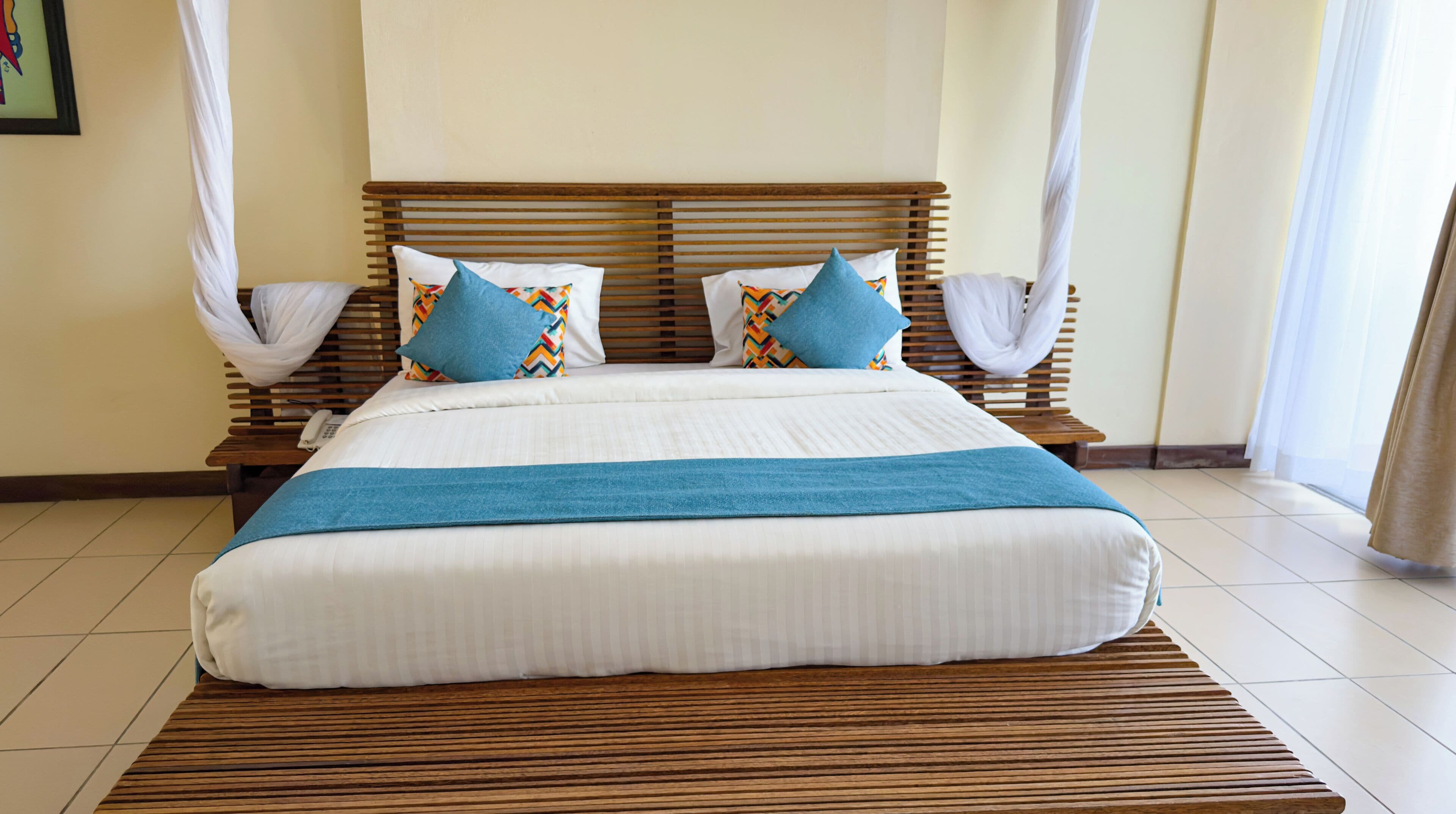 Uma cama com cabeceira de madeira, roupa de cama branca e almofadas azuis.